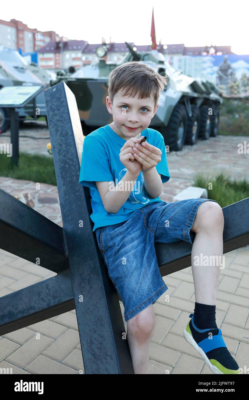 Portrait of boy sitting on anti-tank hedgehog Stock Photo - Alamy