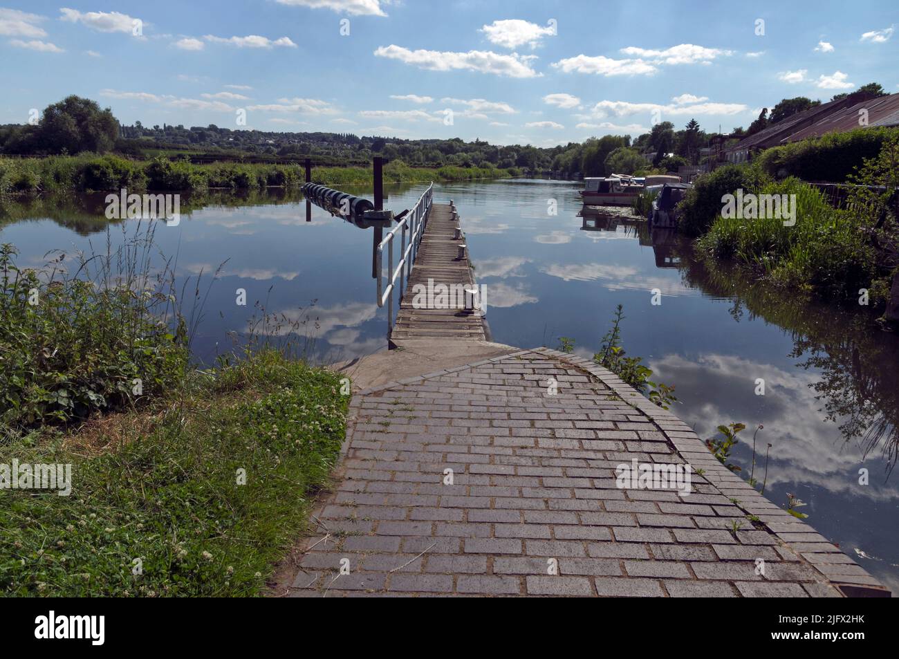 Small wodden pier with still water and refection of clouds on the river ...