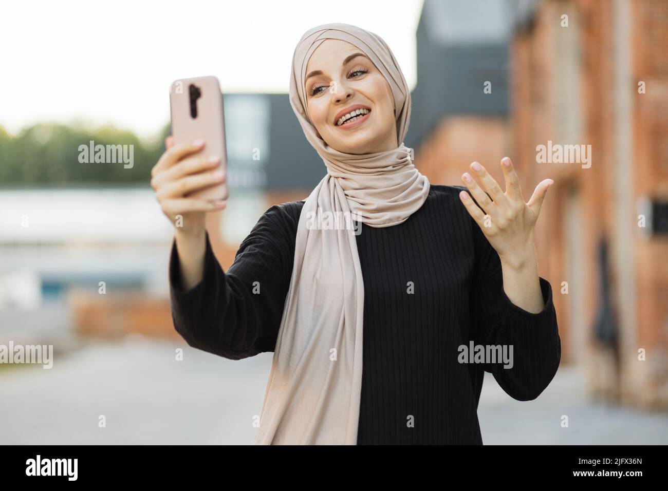 Young Muslim Arab woman in hijab takes a selfie of herself with the ...
