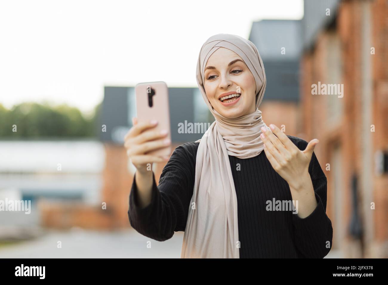Young Muslim Arab woman in hijab takes a selfie of herself with the ...