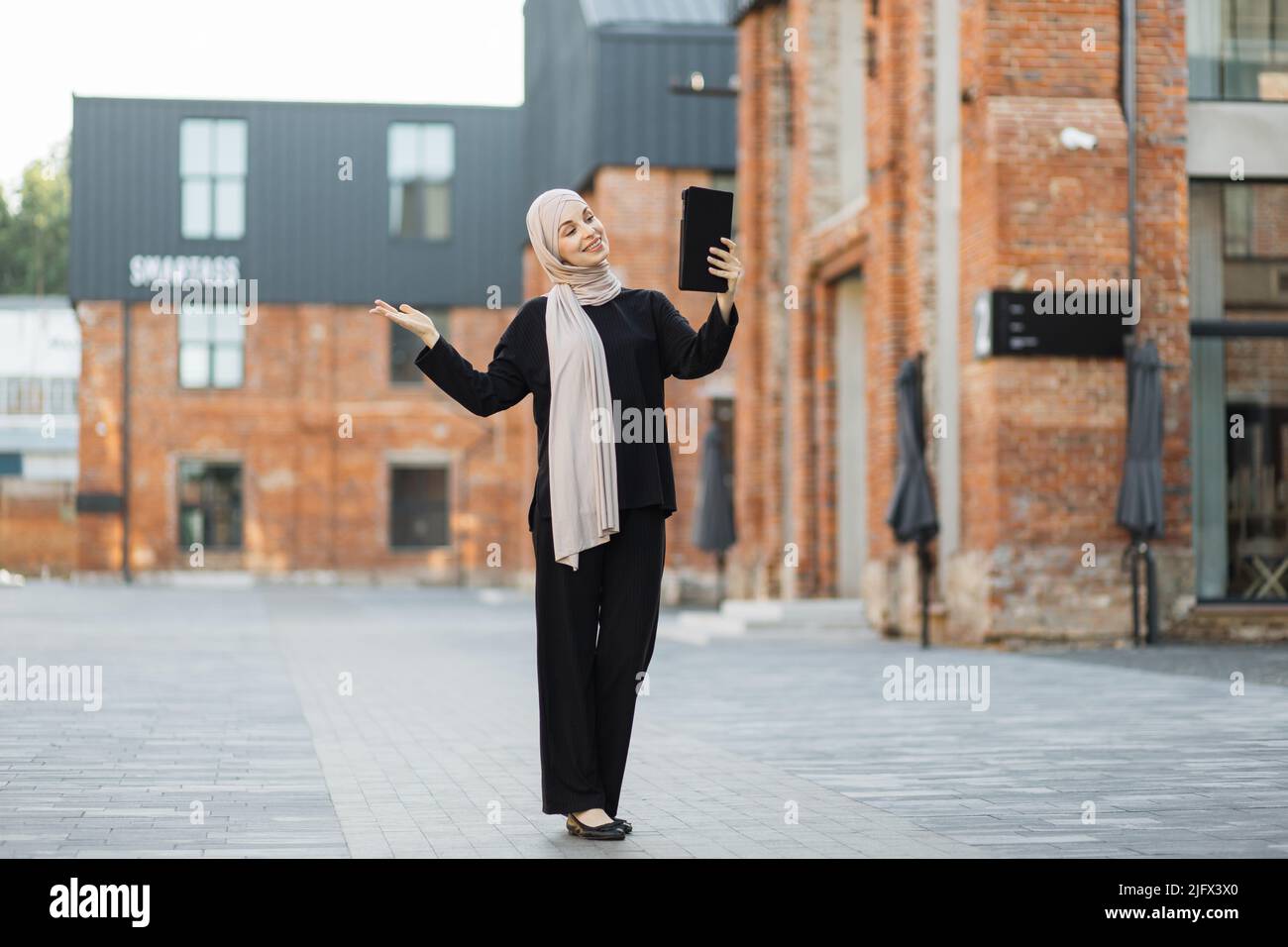 Full lens portrait young Muslim Arab woman in hijab takes a selfie of ...