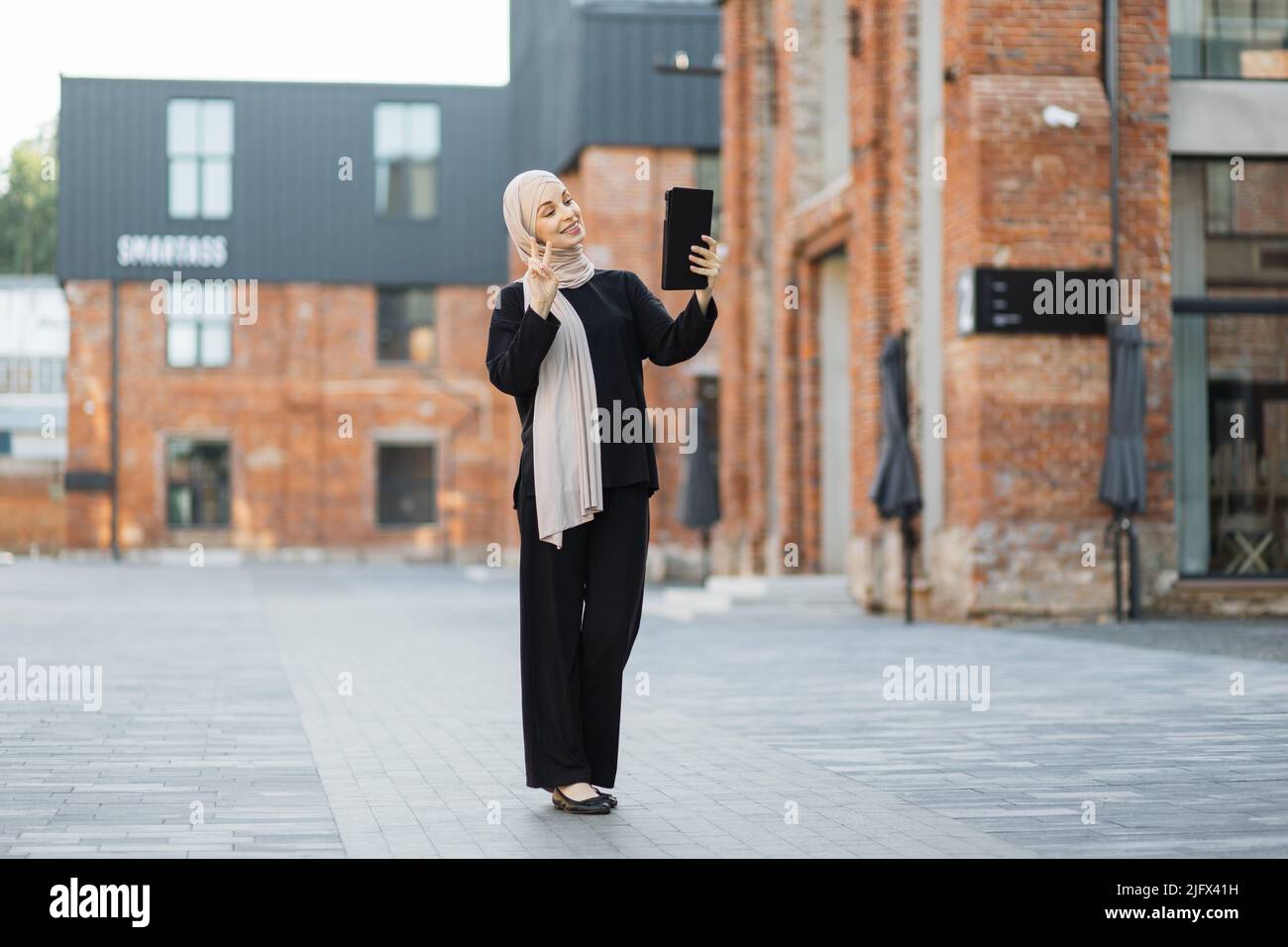 Full lens portrait young Muslim Arab woman in hijab takes a selfie of ...