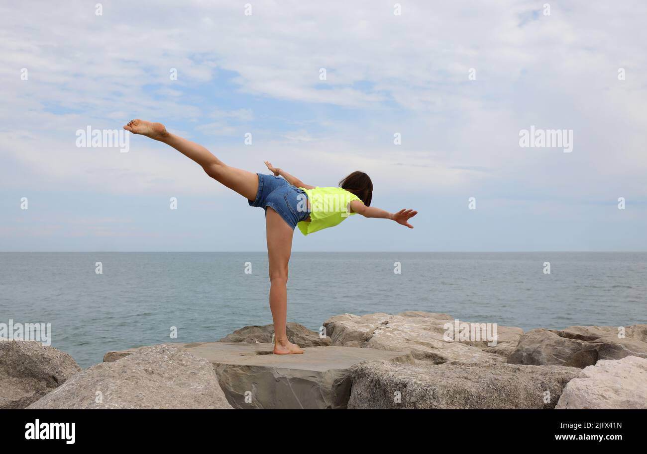 Young slender teenage girl doing balancing exercises on the rocks to ...