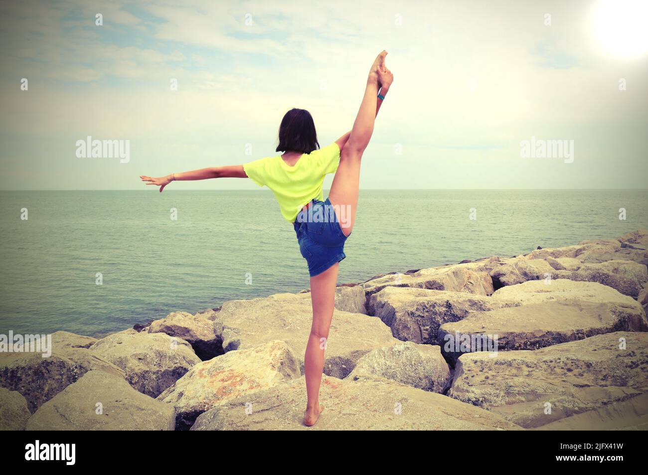 girl does gymnastic exercises to train her balance by straining on one ...