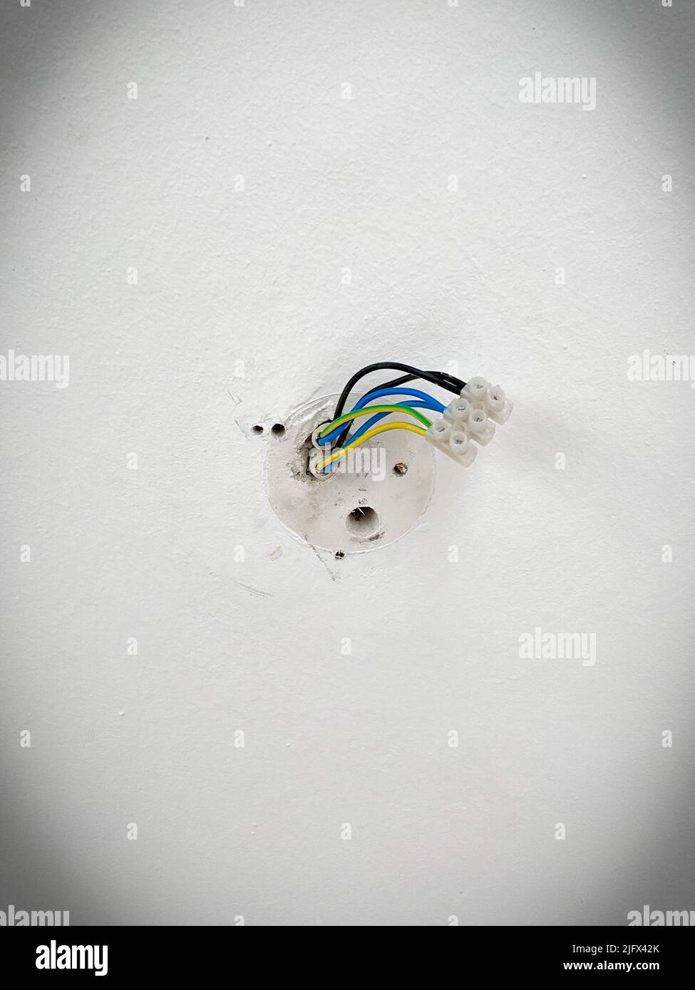 A vertical closeup of an open cable with colorful wires on the wall ...
