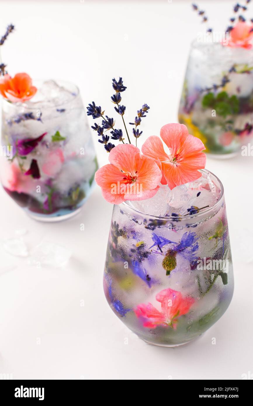 Refreshing cold drink with frozen flowers, cornflowers and geraniums ...