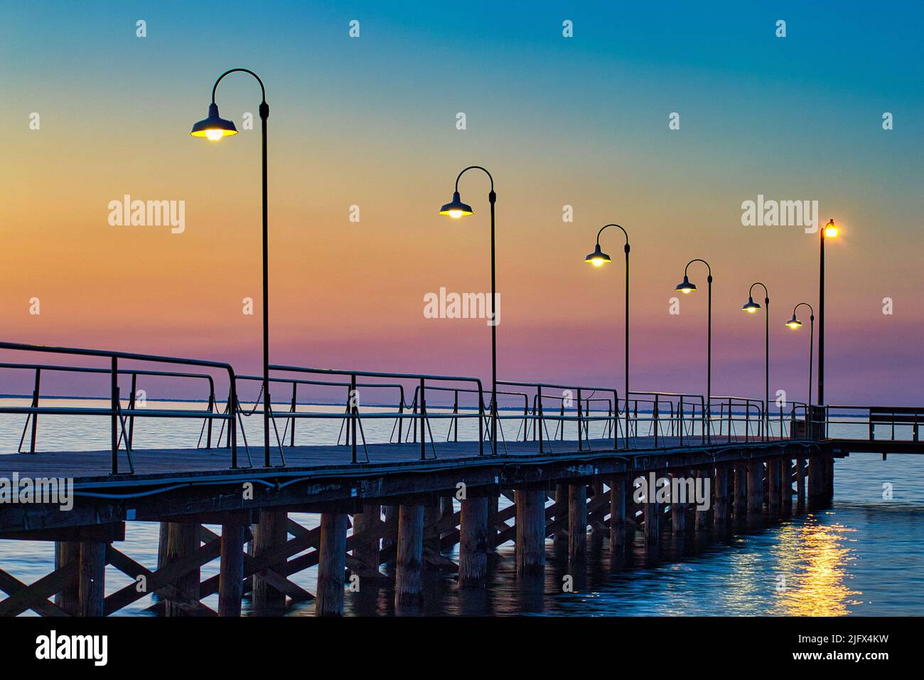 A boardwalk on the water with lights during sunset Stock Photo - Alamy