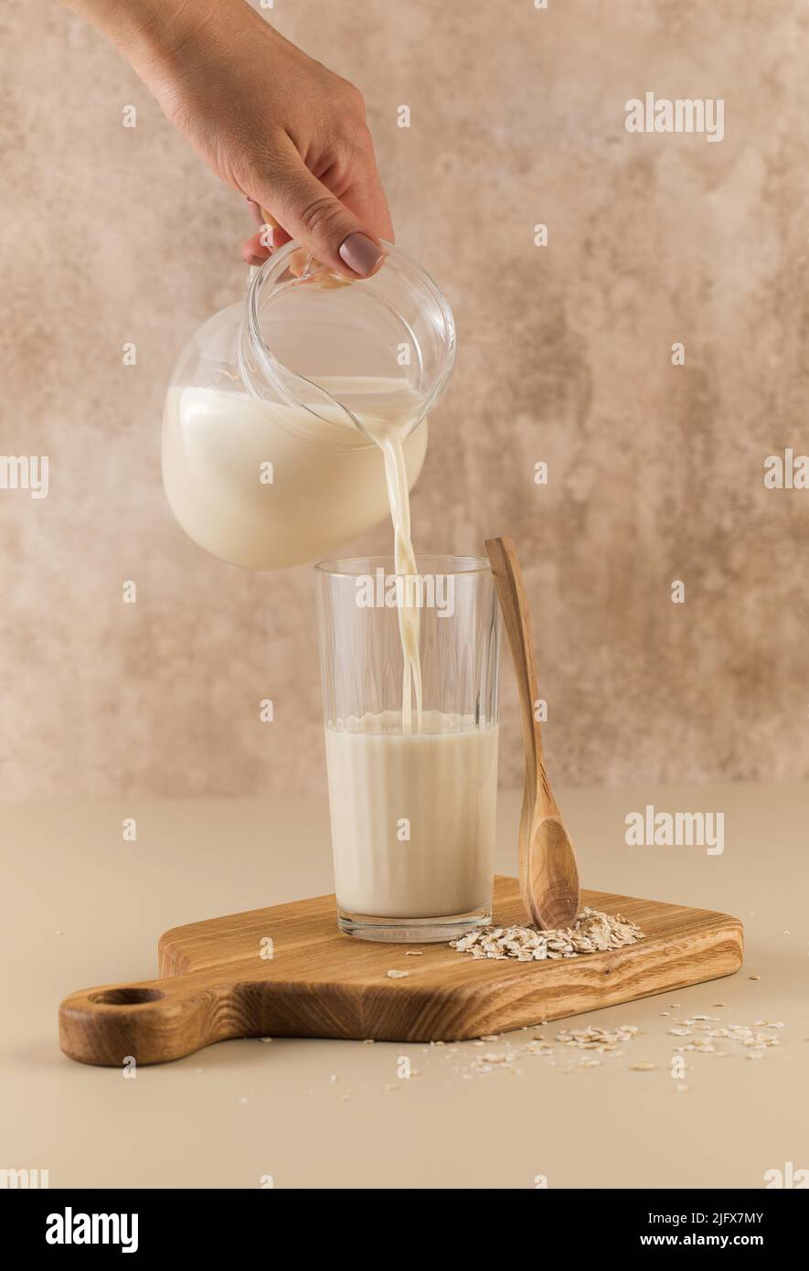 A woman pours oat milk into a mug. Alternative milk. Copy space Stock ...