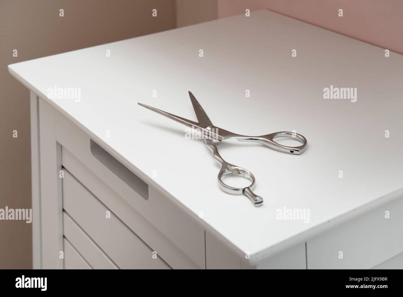 Metal barber scissors on a white chest of drawers Stock Photo - Alamy