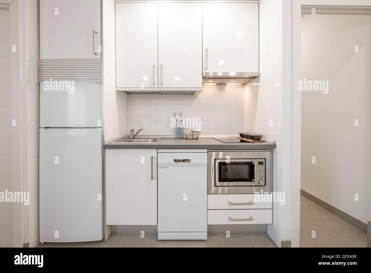 Small kitchen front with white furniture and integrated appliances ...