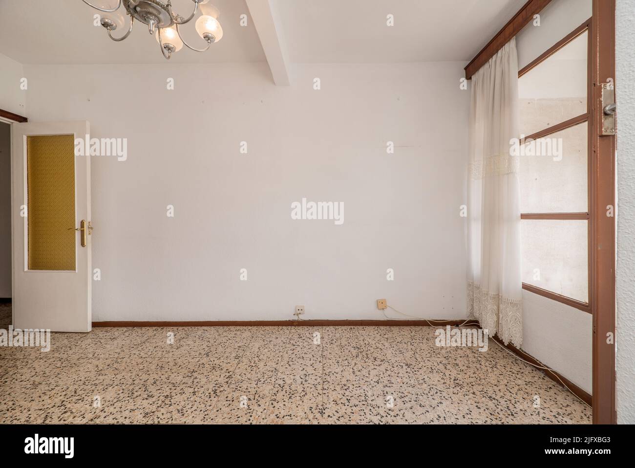 Empty room with old terrazzo floor, white walls and window with access ...