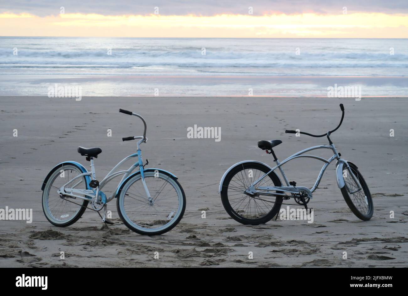 A view of bikes on the ocean beach in the sand at sunset Stock Photo ...