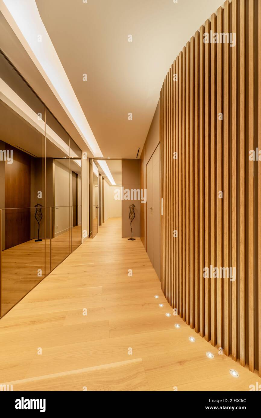 Corridor of a house with a wall covered with mirrors on one side and ...