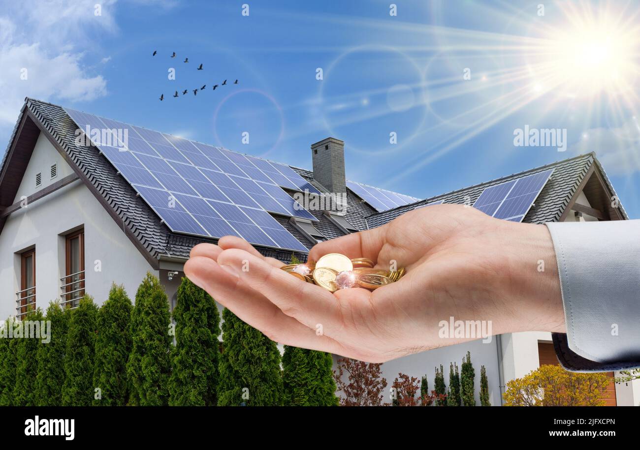 Solar panel on roof of house and coins in hand. Concept of money saving ...
