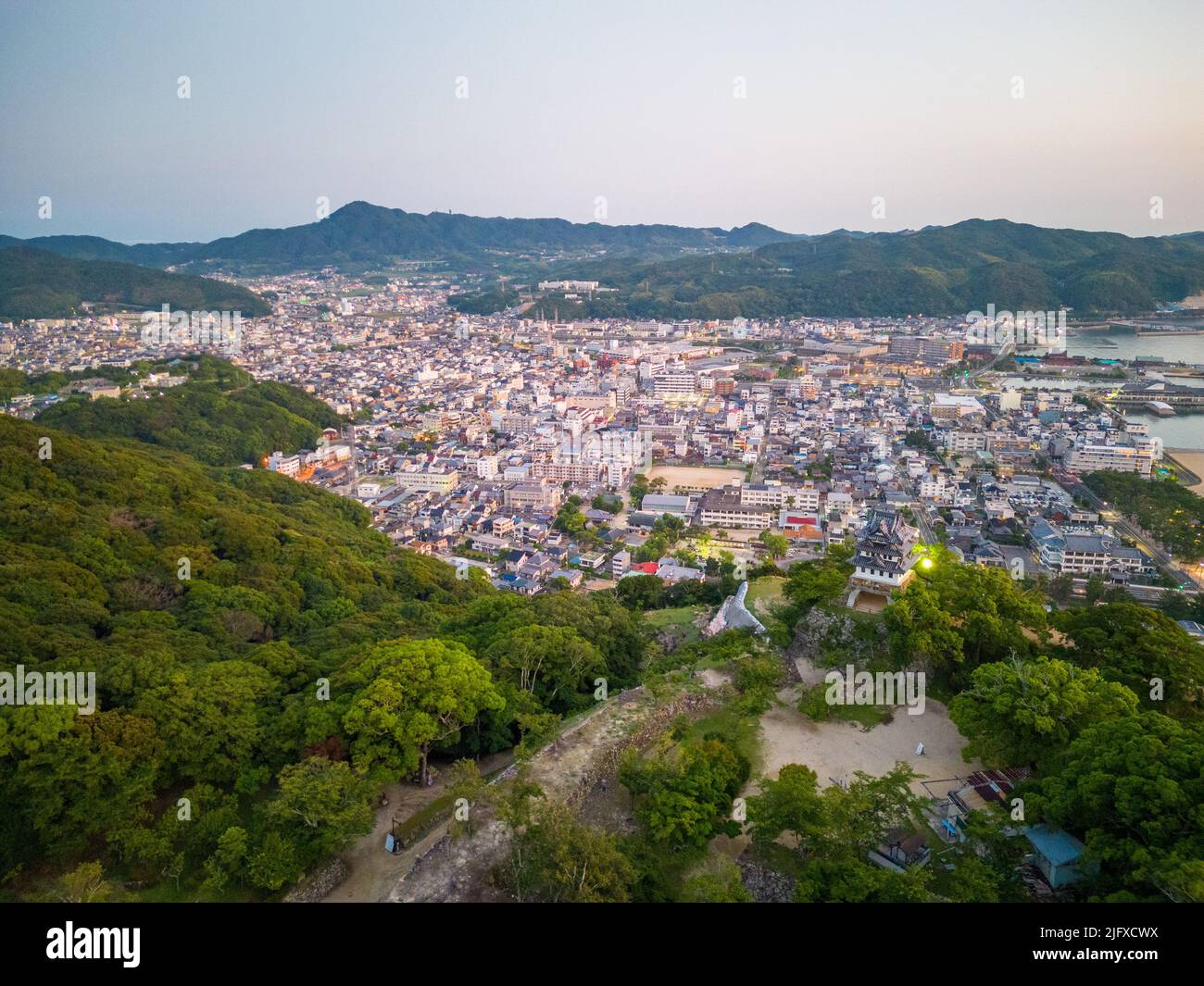 Small town spread through valley between green hills in early morning ...