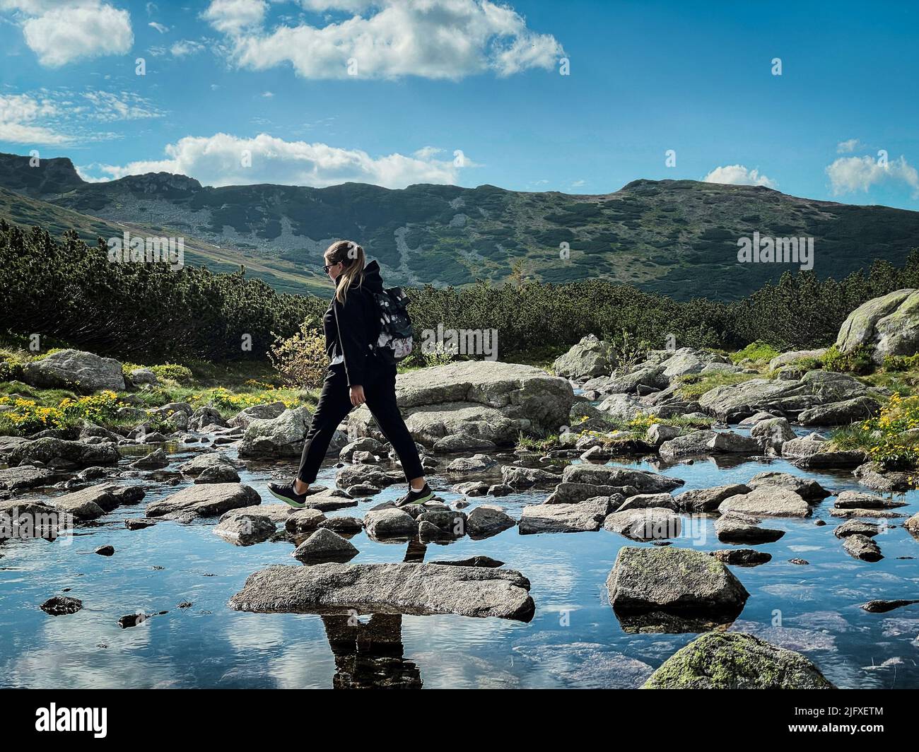Woman walking across river rocks hi-res stock photography and images ...