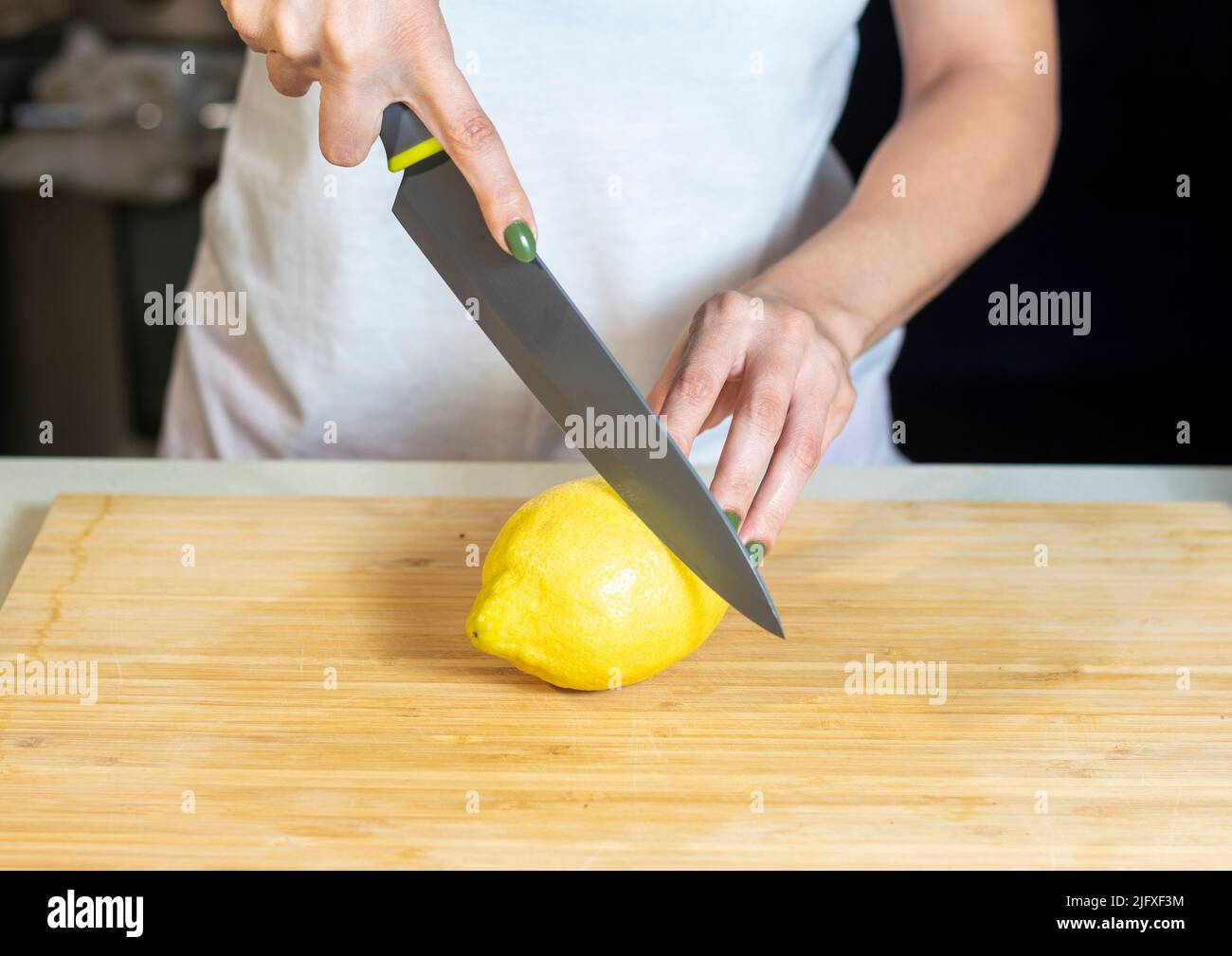 Close up of young woman hands cutting lemon on wooden cutting bo Stock ...