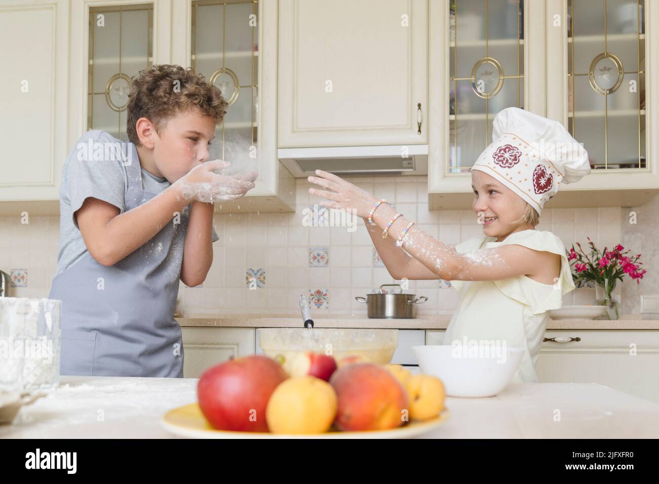 Brother and sister have fun playing with flour in the kitchen Stock ...