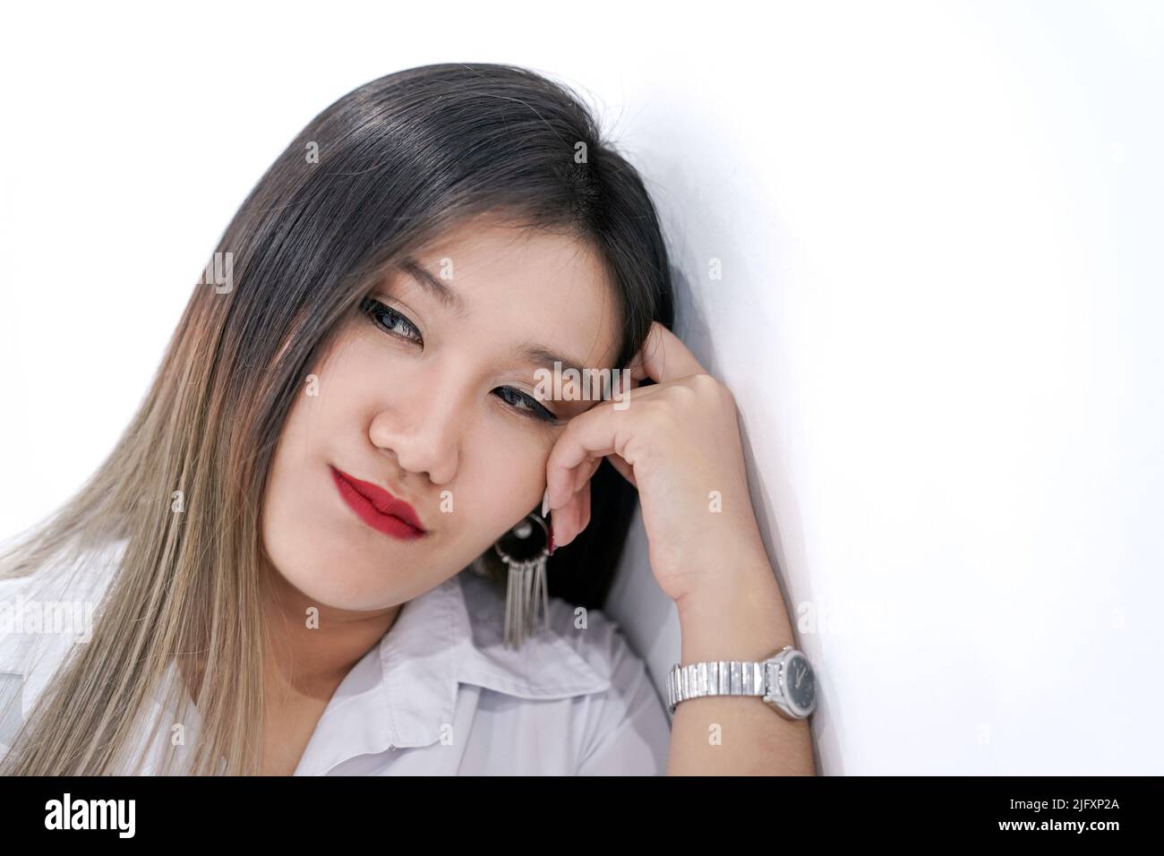 A young Asian woman is making a cheeky face and squinting at something ...