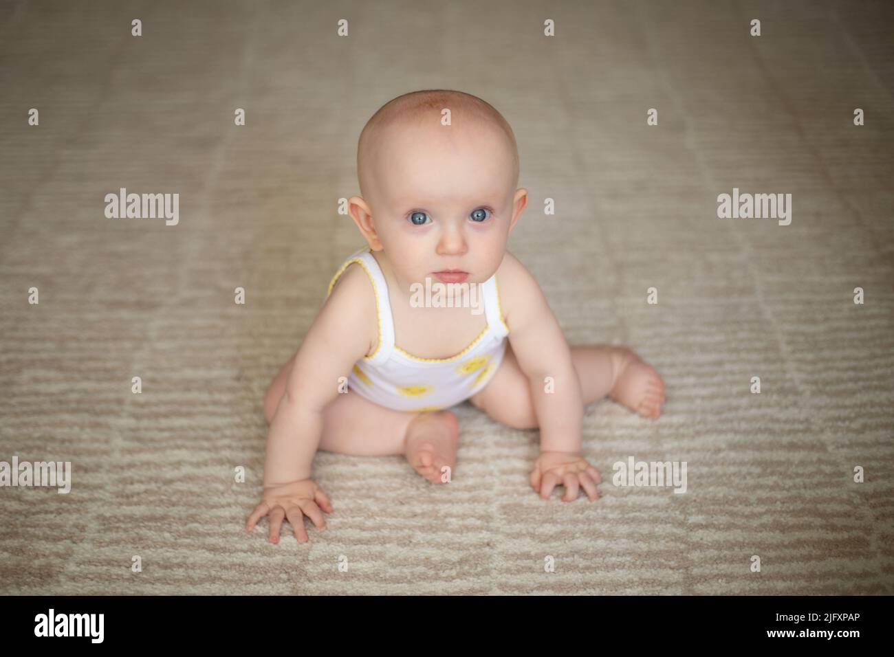 Adorable happy little baby girl sitting on furry carpet at home Stock ...