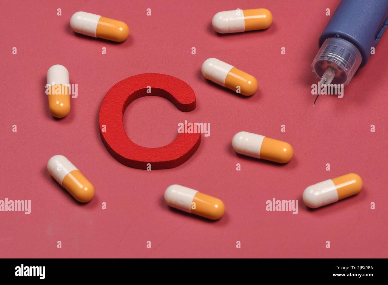 yellow and white medicine capsules on red background and insulin pen ...