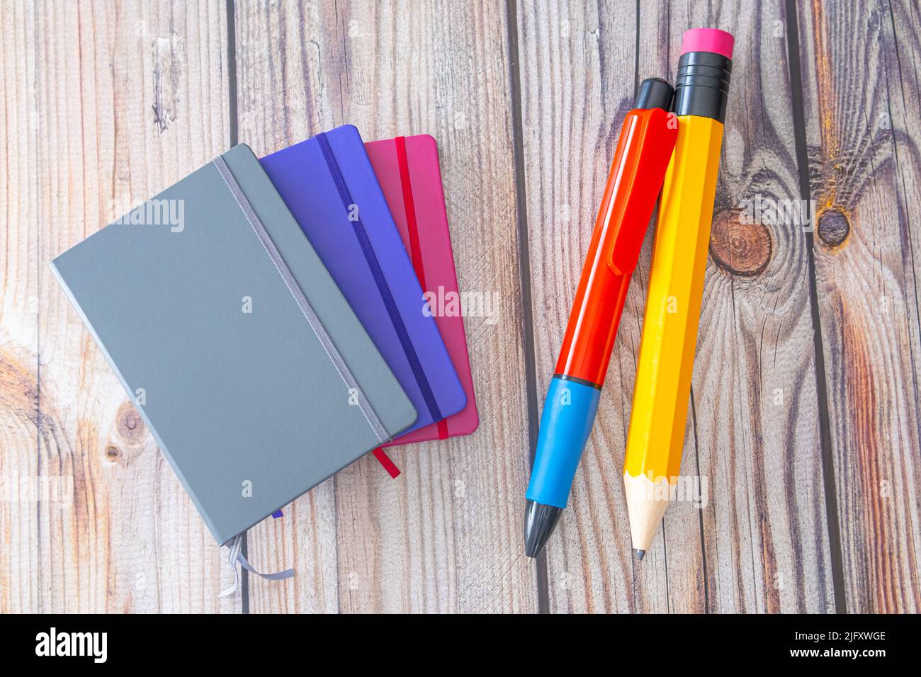 Stack of Journals notebooks with giant pen and pencil Stock Photo - Alamy