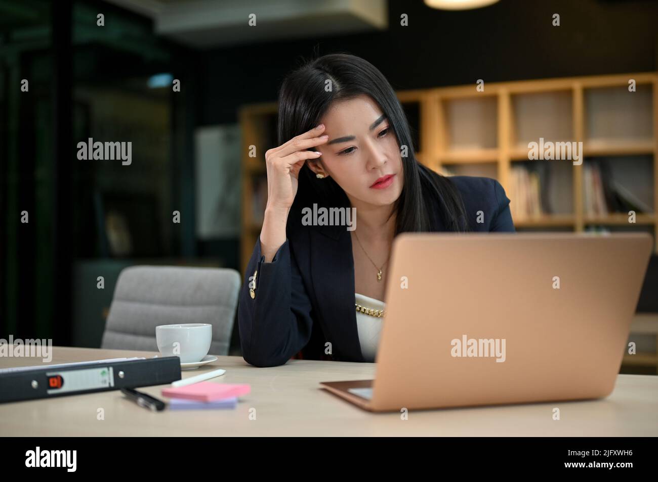 Stressed and serious asian businesswoman or female manager using laptop ...