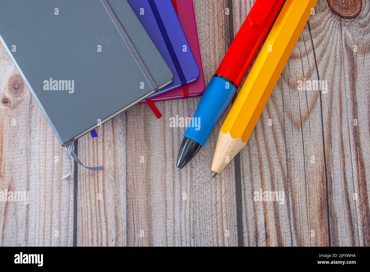 Stack of Journals notebooks with giant pen and pencil Stock Photo - Alamy