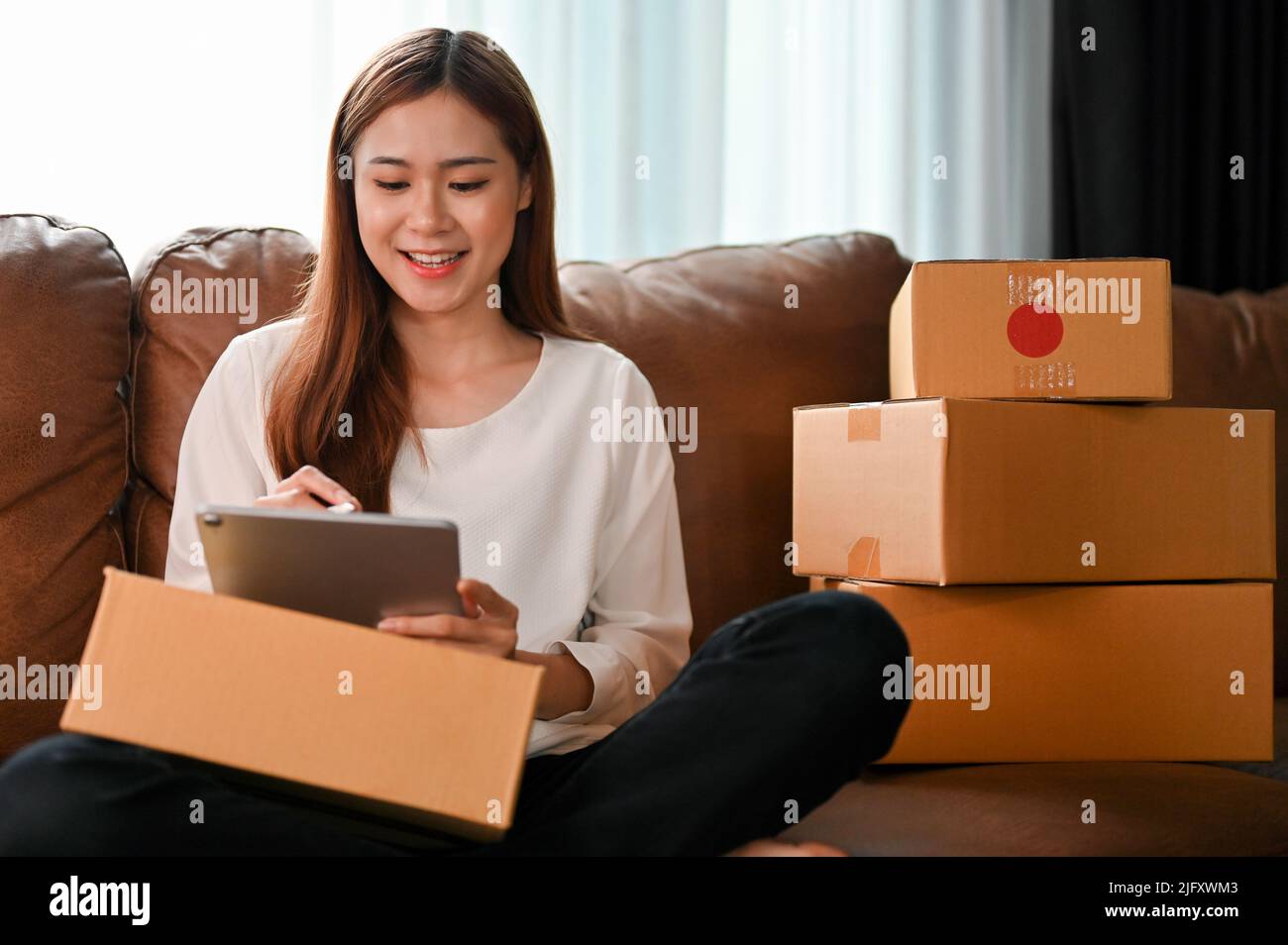 Beautiful young Asian female small online shop owner using portable ...