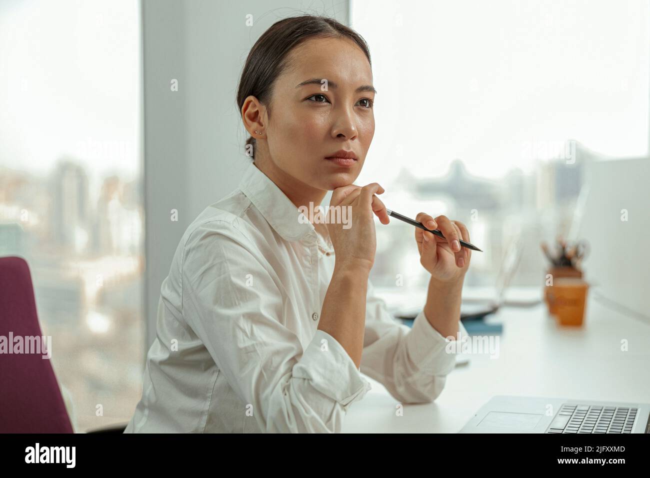 Portrait of focused asian business woman sitting in office on her ...