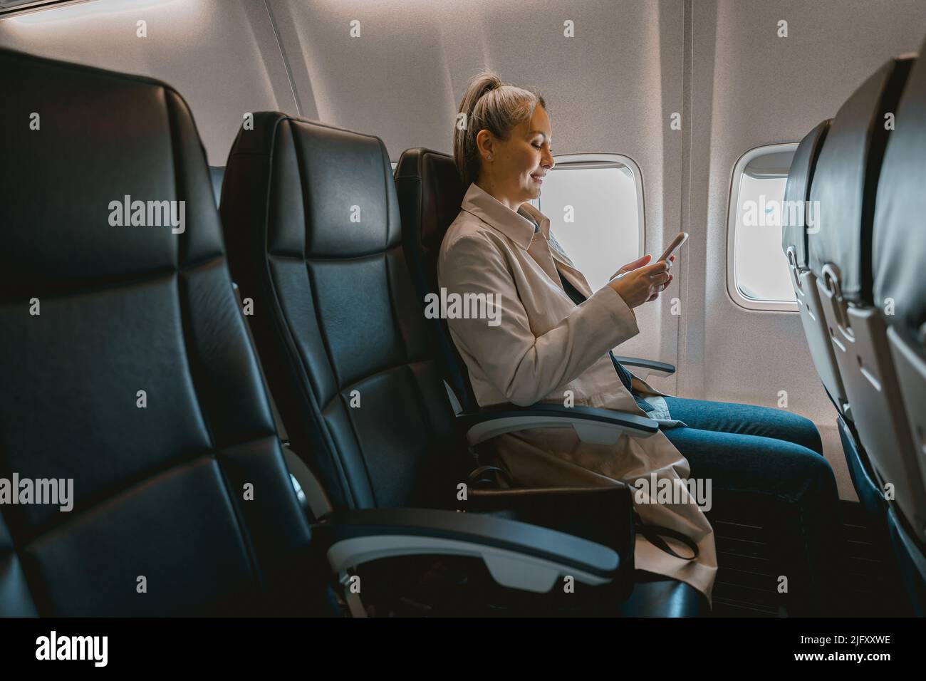 Beautiful Asian woman passenger sitting in the airplane and use phone during boarding Stock ...