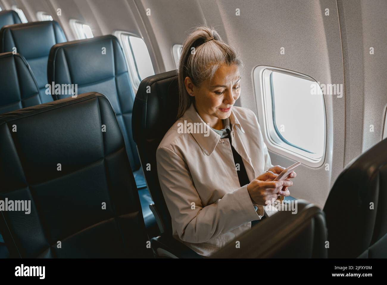 Beautiful Asian woman passenger sitting in the airplane and use phone during boarding Stock ...