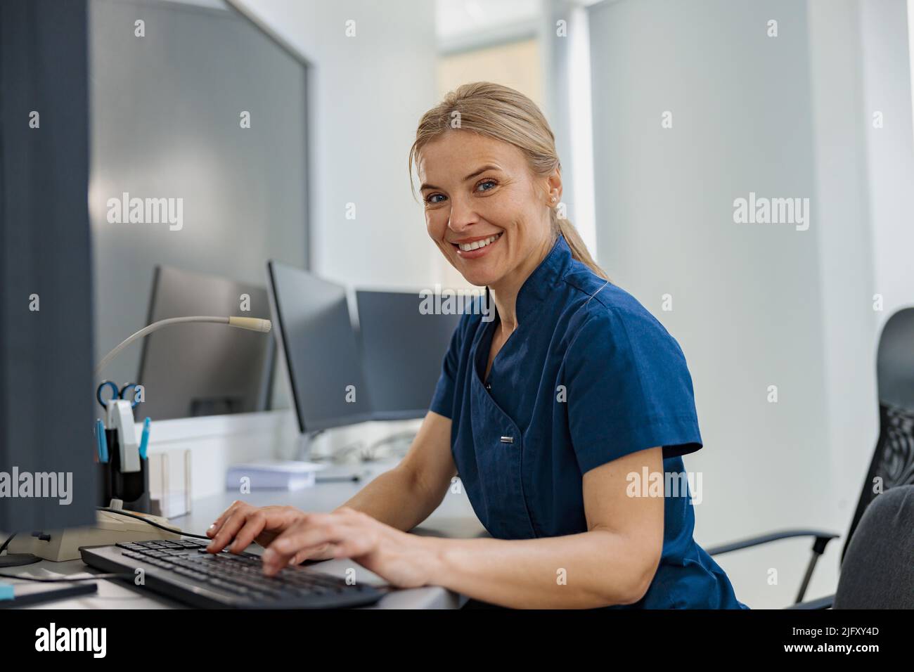 Nurse on Duty working on computer at the Reception Desk in modern ...