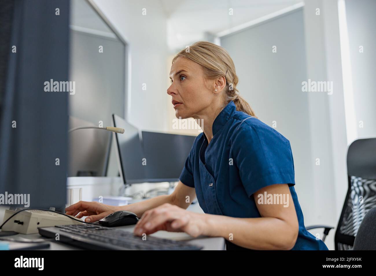 Nurse on Duty working on computer at the Reception Desk in modern ...