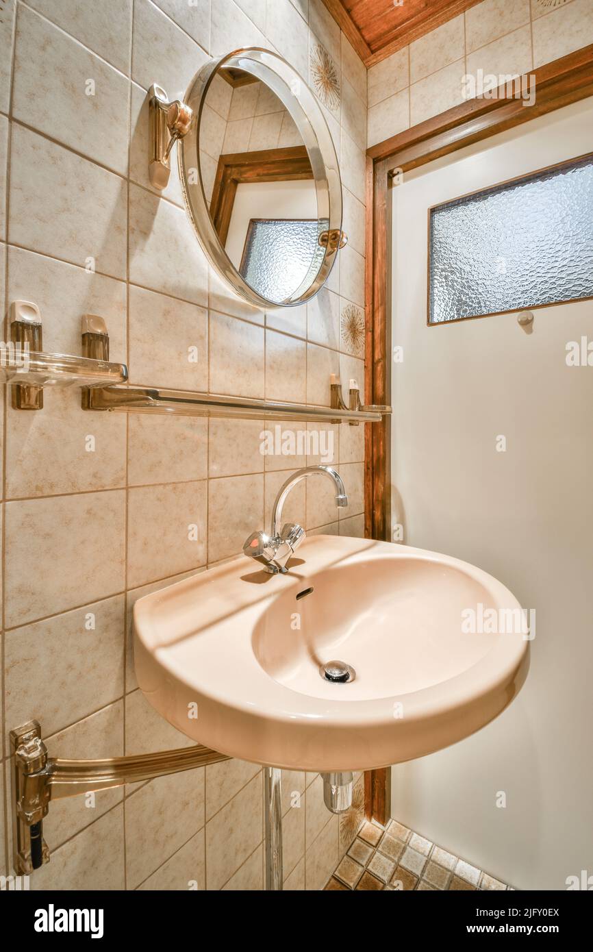 Cupboard with sink and mirror attached to tiled wall near door and ...