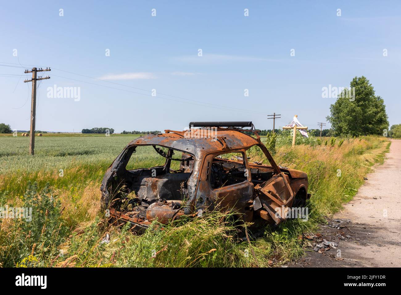 A burned-out car on the side of the road against the background of a ...