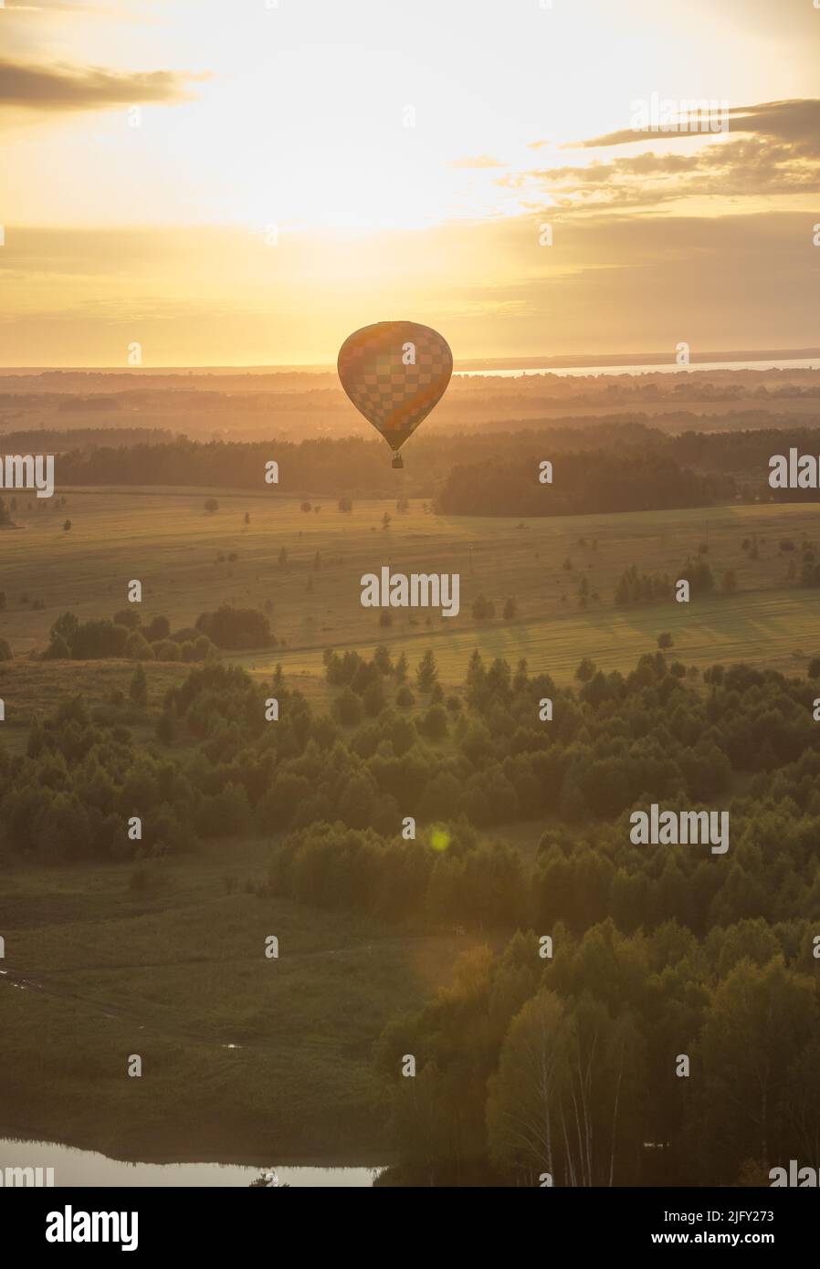 An air balloon flying over the field and trees using heat technology ...