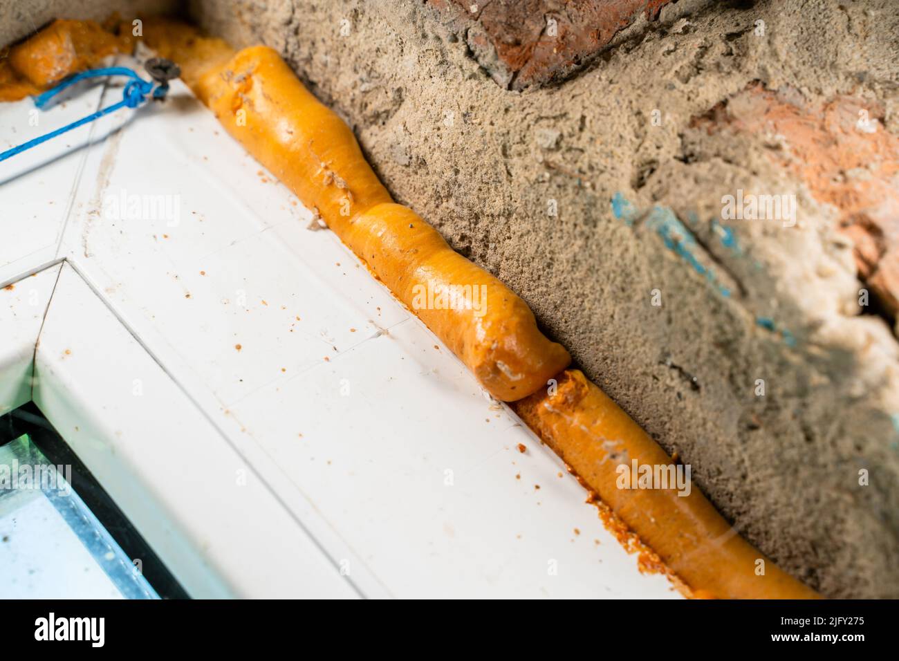 Old mounting foam between a plastic window and a brick wall close-up ...
