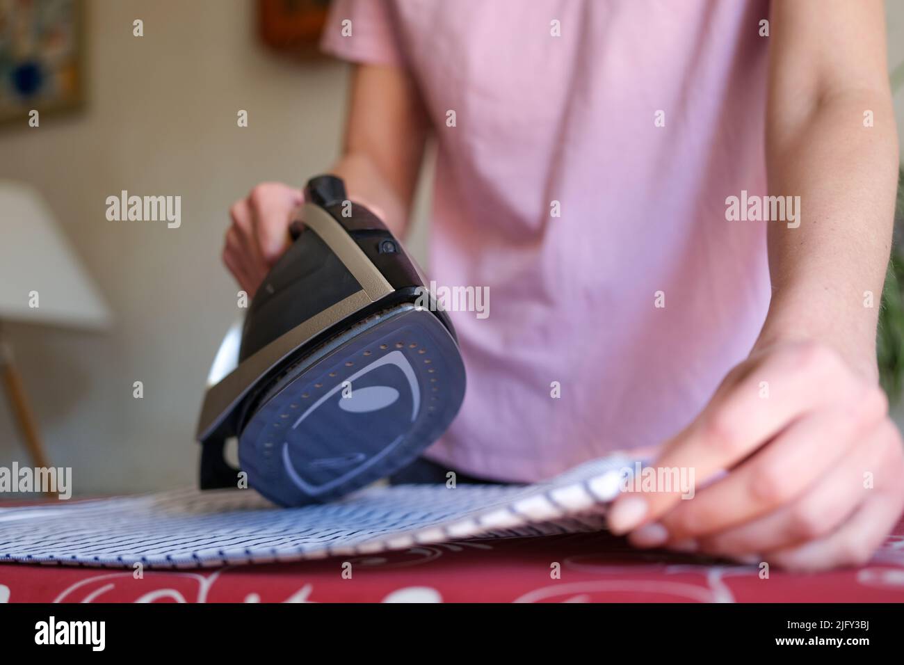 Woman ironing bed linen on special board using steam iron Stock Photo ...