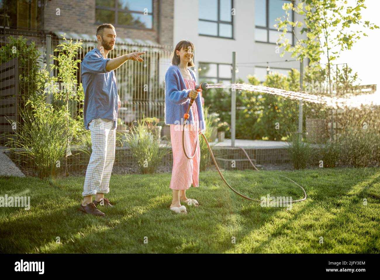 Lovely couple watering lawn at backyard Stock Photo - Alamy