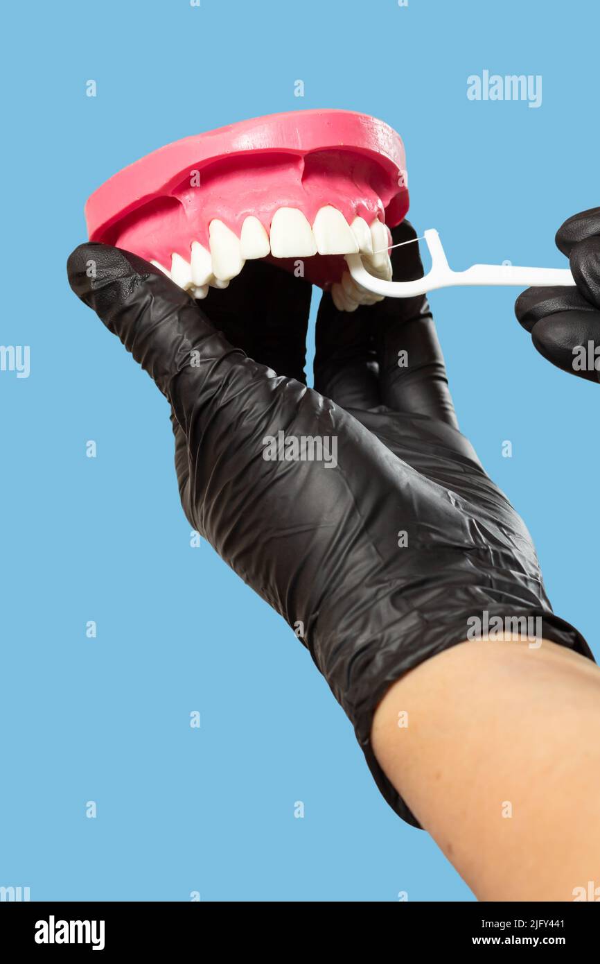 Close-up view of the hand with a human jaw layout and a floss toothpick ...