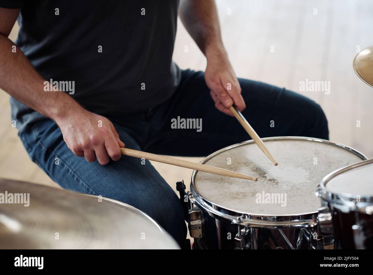 Close-up of young drummer beating with drumsticks on drums during ...