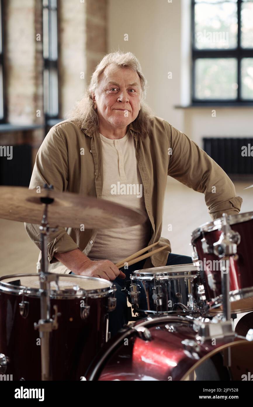 Portrait of mature rock musician with gray hair looking at camera while ...