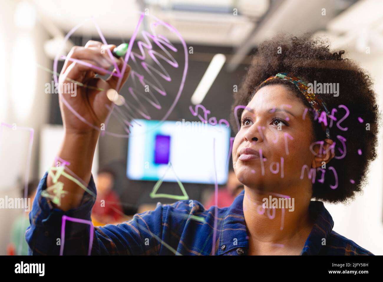 Young african american female app developer drawing chart on glass in ...