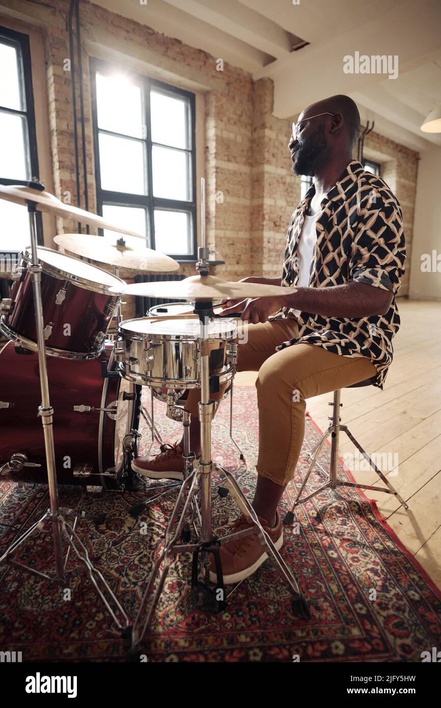 African young drummer sitting at drum set playing with sticks ...