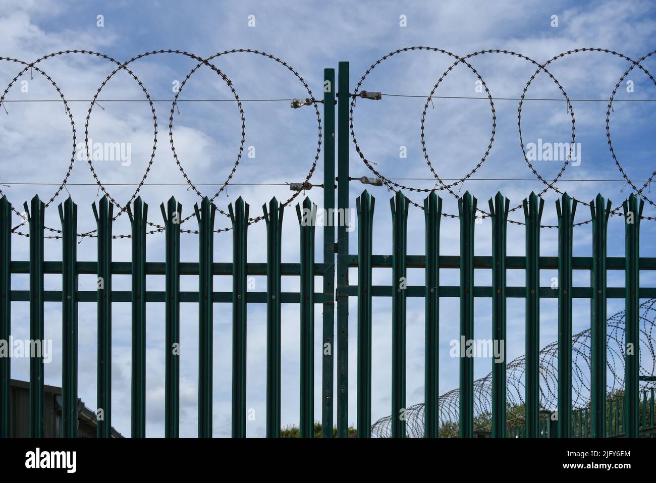Metal security gates topped with razor wire Stock Photo - Alamy