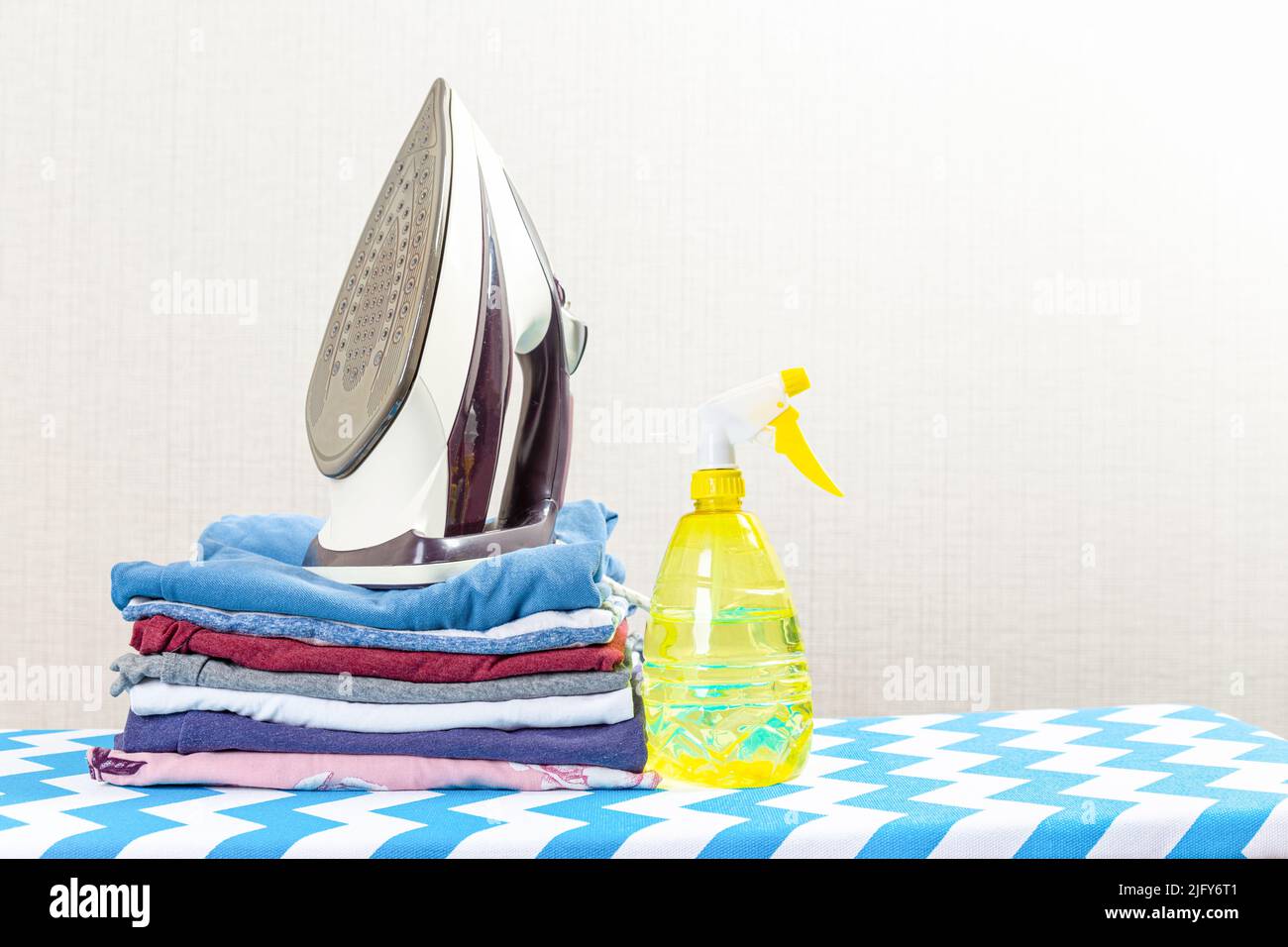 Electric iron on ironing board and water spray for ironing Stock Photo ...