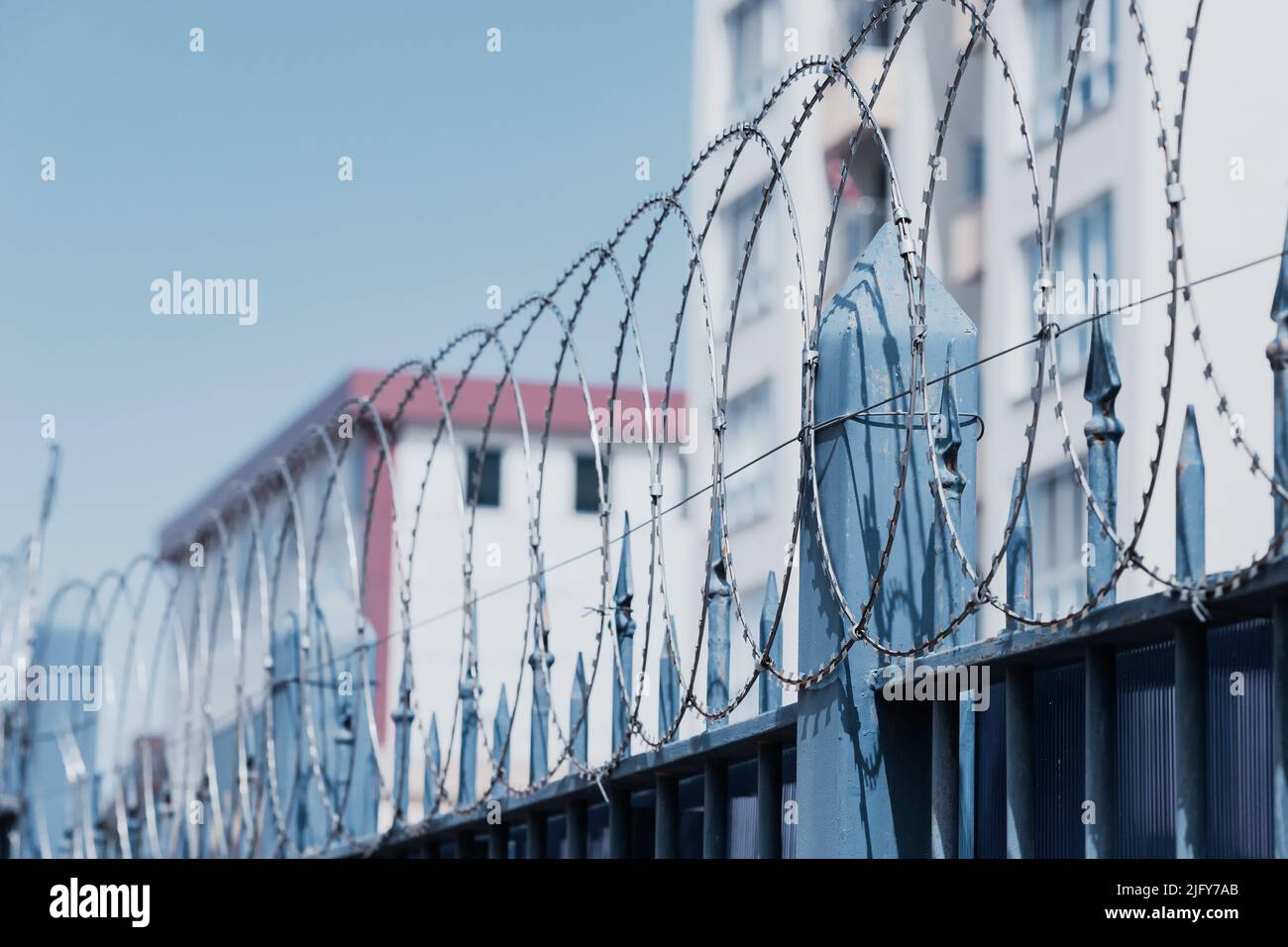 Barbed wire and metal fence at the entrance to prison or military base ...