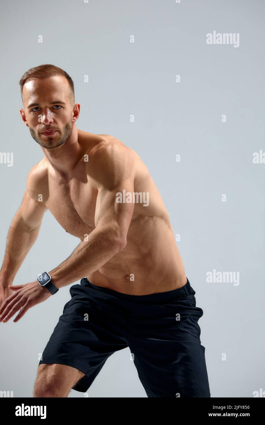 Developing endurance. Male athlete in motion isolated over gray studio ...