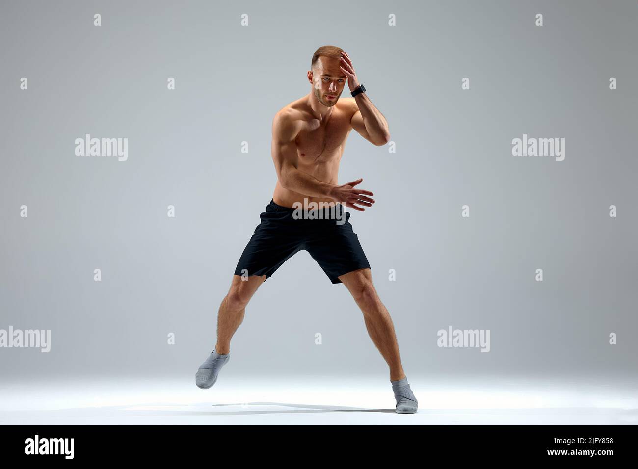 Developing endurance. Male athlete in motion isolated over gray studio ...